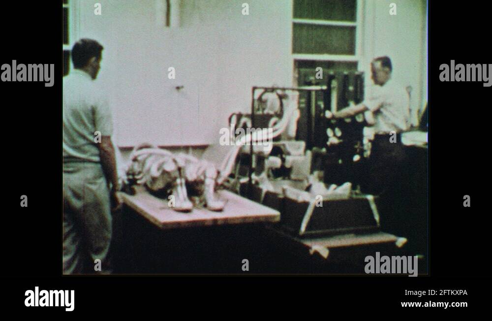 1950s- A fully suited astronaut lays on a table while two scientists ...
