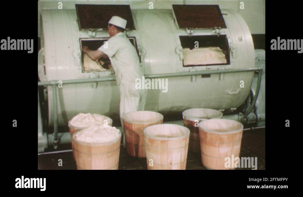 1940s: Dairy worker removing butter from a large cylindrical churn with ...