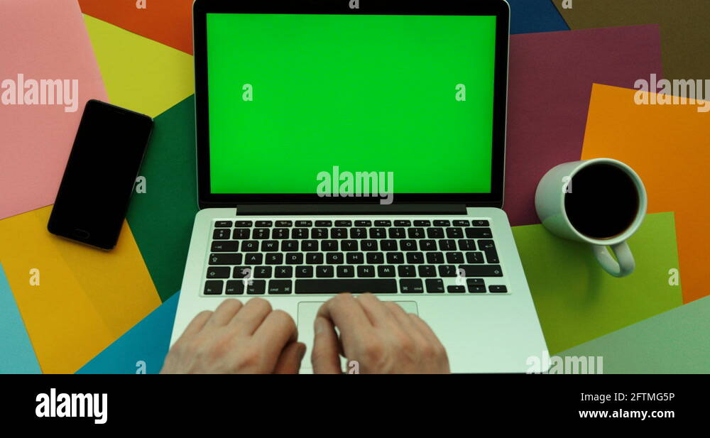 Man typing on laptop with green screen on colorful beackground. Male ...