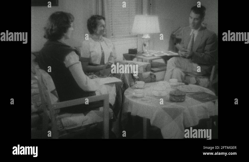 1950s: Teacher talks to couple, man hands teacher paper / Teacher looks ...