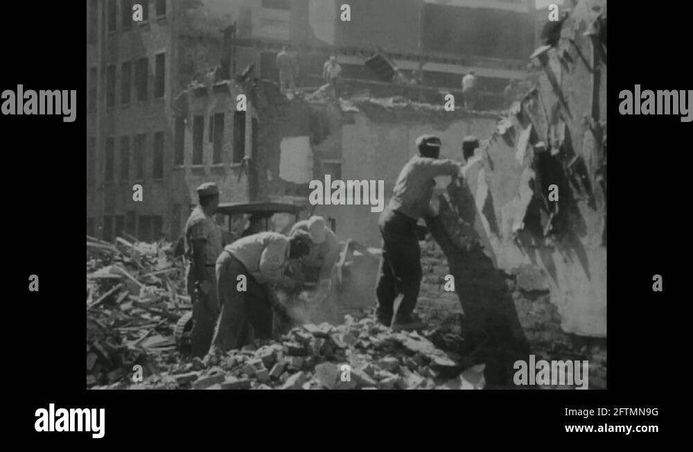 1950s: Construction workers in rubble / Worker, pan across rubble ...