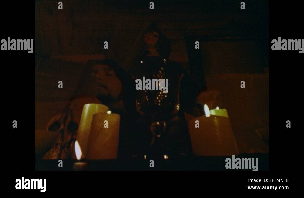 1970s - A robed cult leader lifts a chalice before passing it to others ...