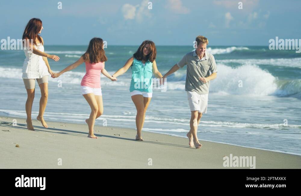 A healthy Caucasian family walking and having fun together at the beach ...