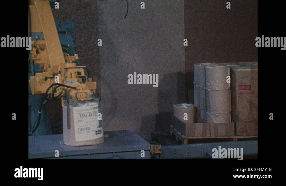 1980s: industrial robotic arm in a factory carries cylindrical objects ...