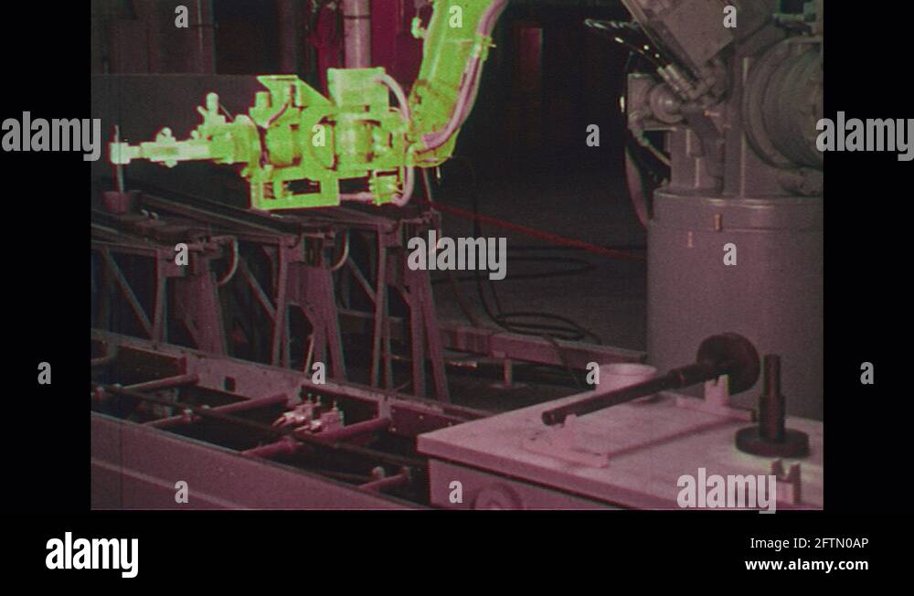 1980s: industrial robotic arm works at assembly line. It places part on ...