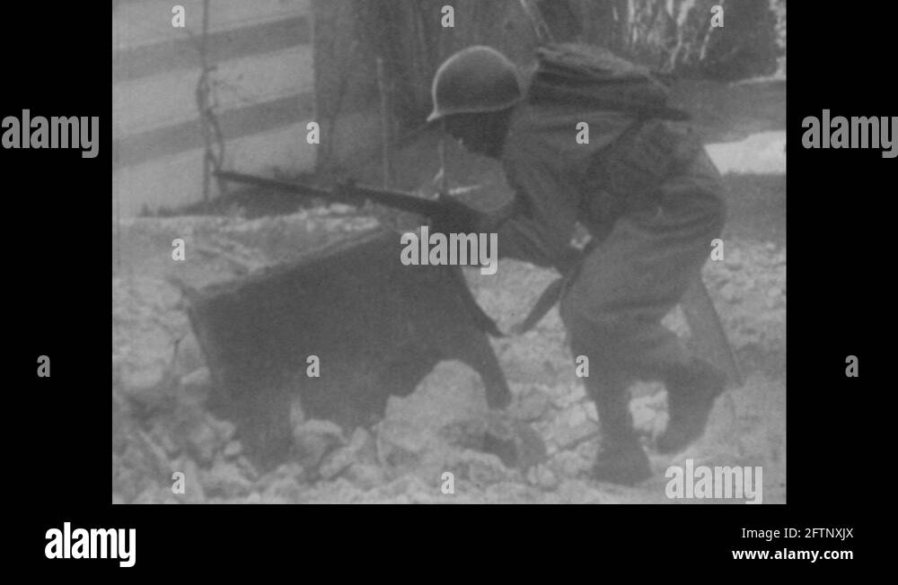 1950s: Armed soldier crouches behind object on battle field. Overhead ...