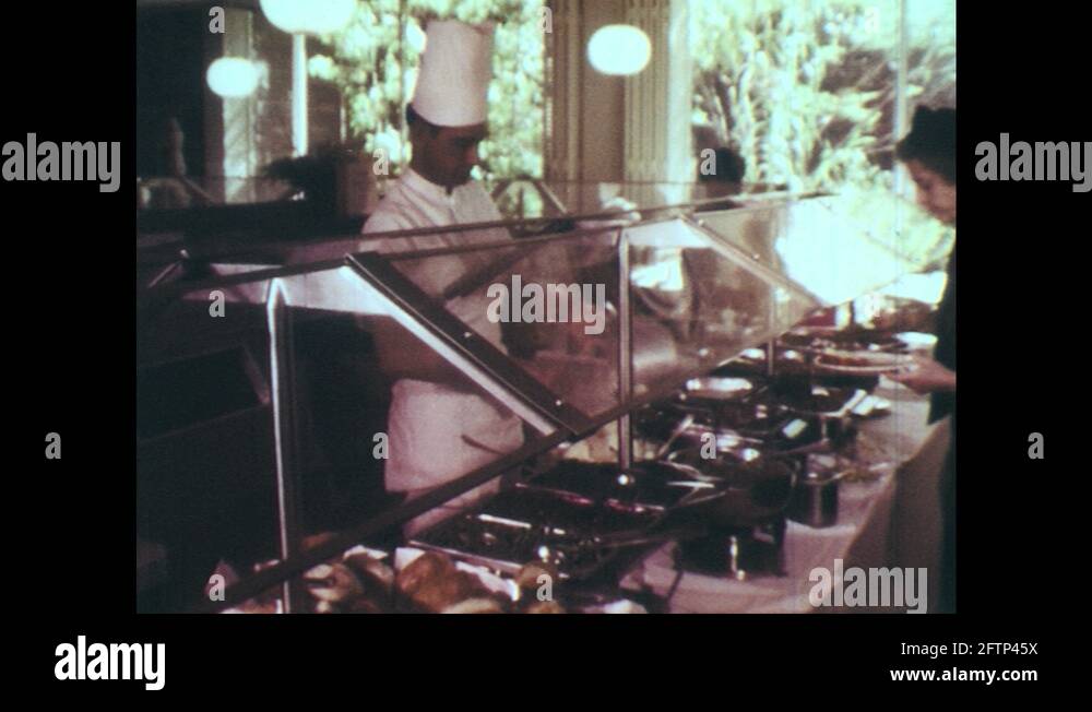 UNITED STATES: 1950s: chef serves food from buffet. Diners eat at ...
