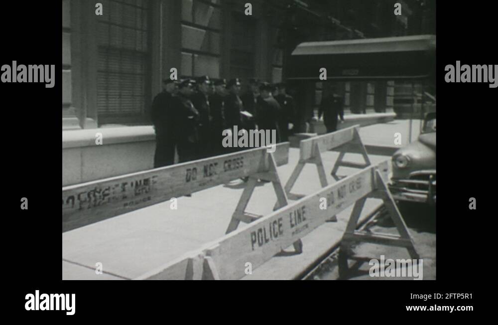 UNITED STATES: 1950s: Police stand behind police line. People in street ...
