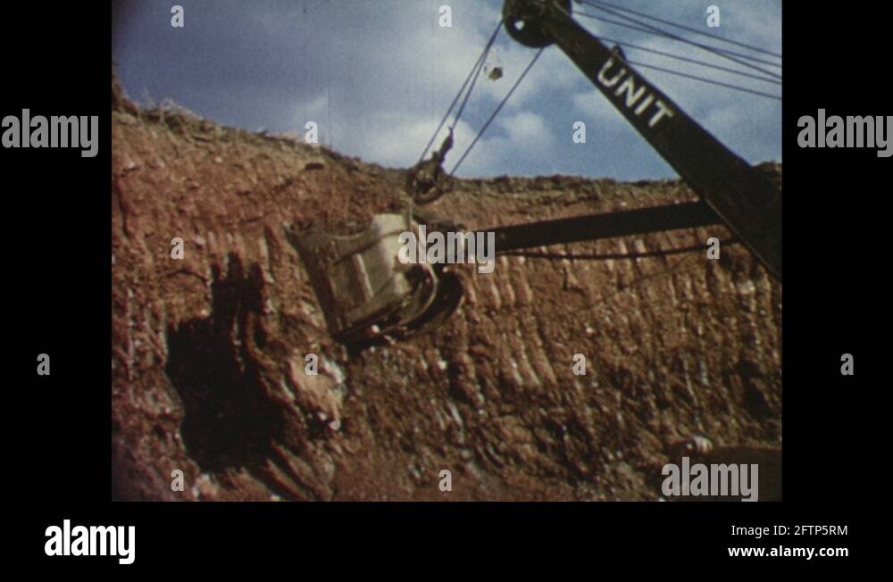 1950s: Bucket on digger scoops soil from large hole. Dust in machine ...