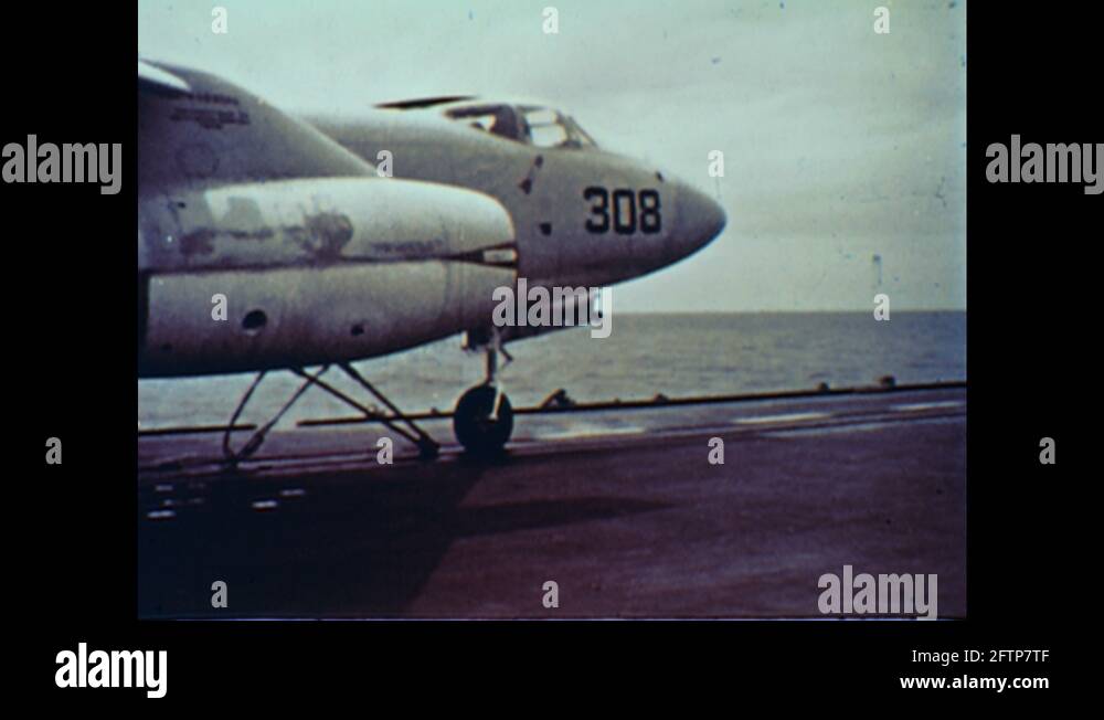 United States: 1960s: fast jet takes off from deck of ship. Navy men on ...