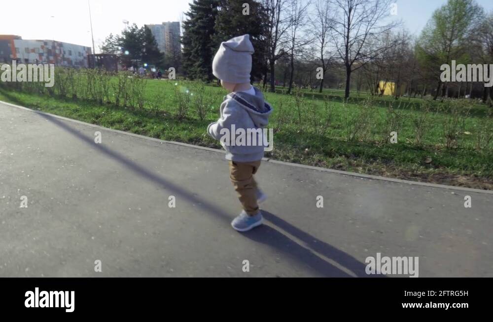 Little cute boy with confident rapid steps walks along the alley in the ...