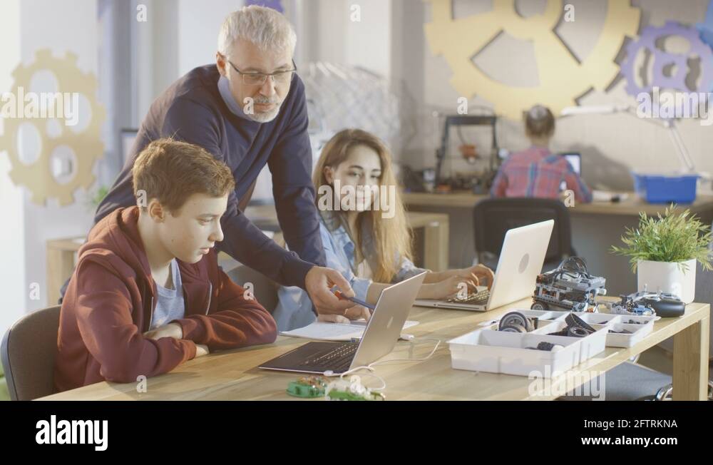 Teacher Works with Young Boy and Girl in a Computer Science Class Stock ...