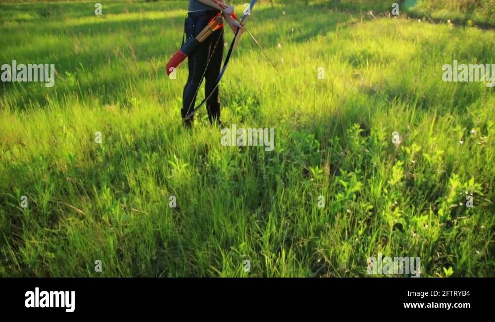 Female ginger hair archer shooting targets with her bow and arrow with ...
