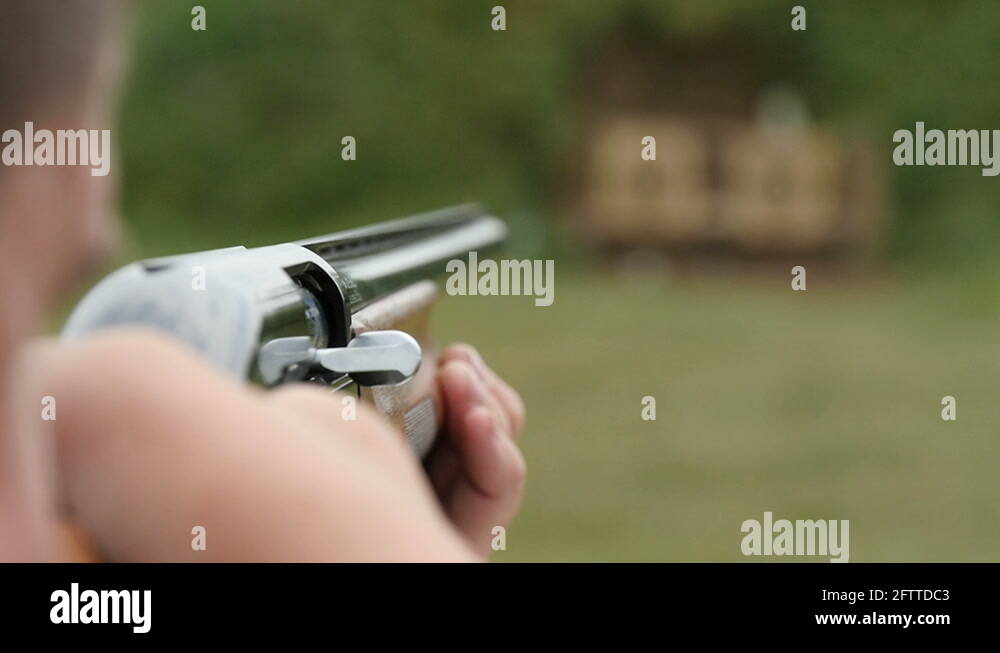 Some man aiming and shooting from a skeet shooting rifle in slow motion ...