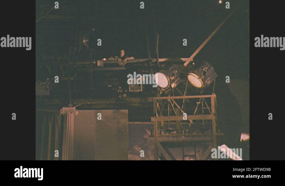 1960s: man plays piano on movie soundstage. men operate boom microphone ...