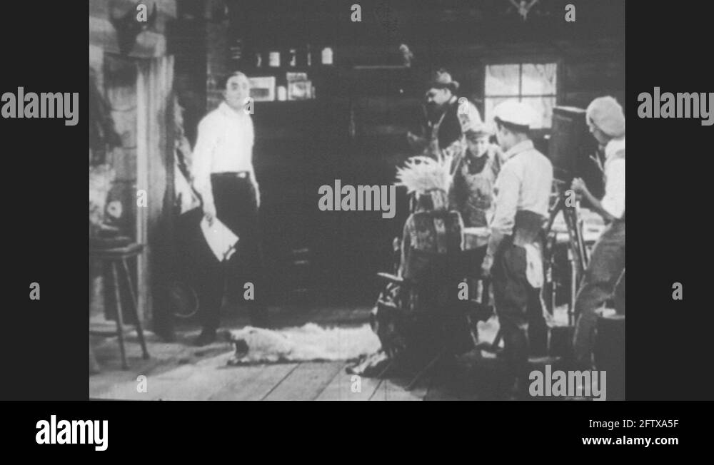 1920s Man Points Around Room At Men And Sits Next To Movie Camera 1920s Man Points Around Room At Men And Sits Next To Movie Camera