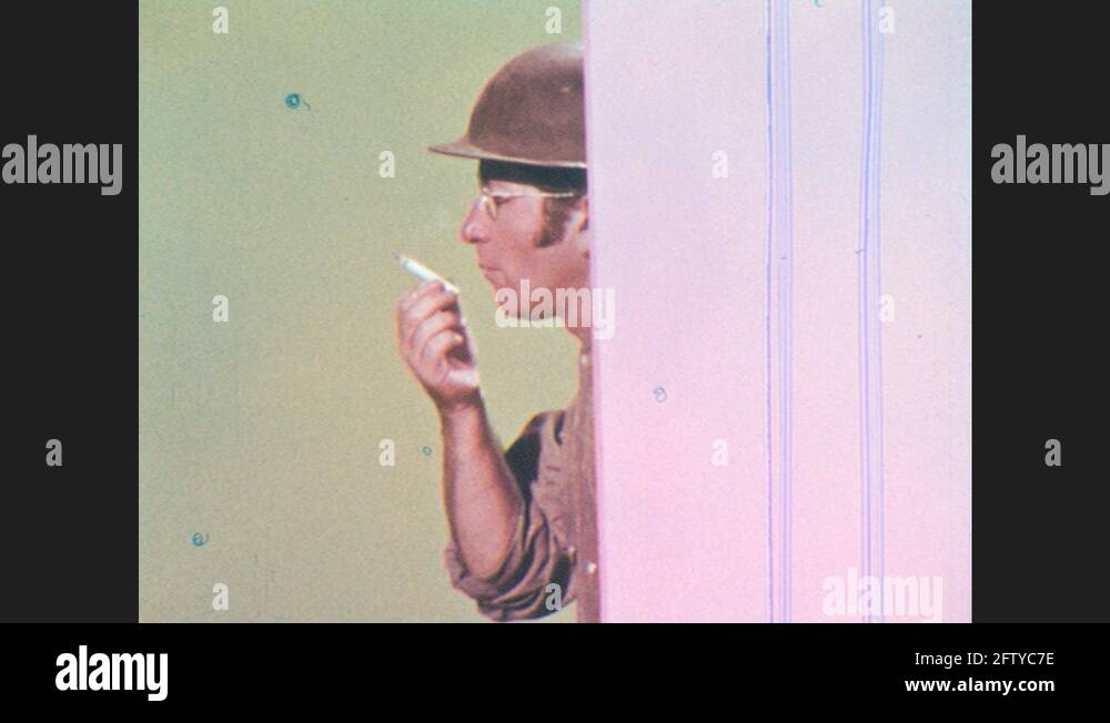 1970s: Man in army helmet peers around, smokes cigarette, and talks ...