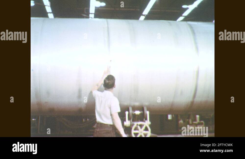 1960s: Man touches rocket booster tank. Man walks by rocket booster ...