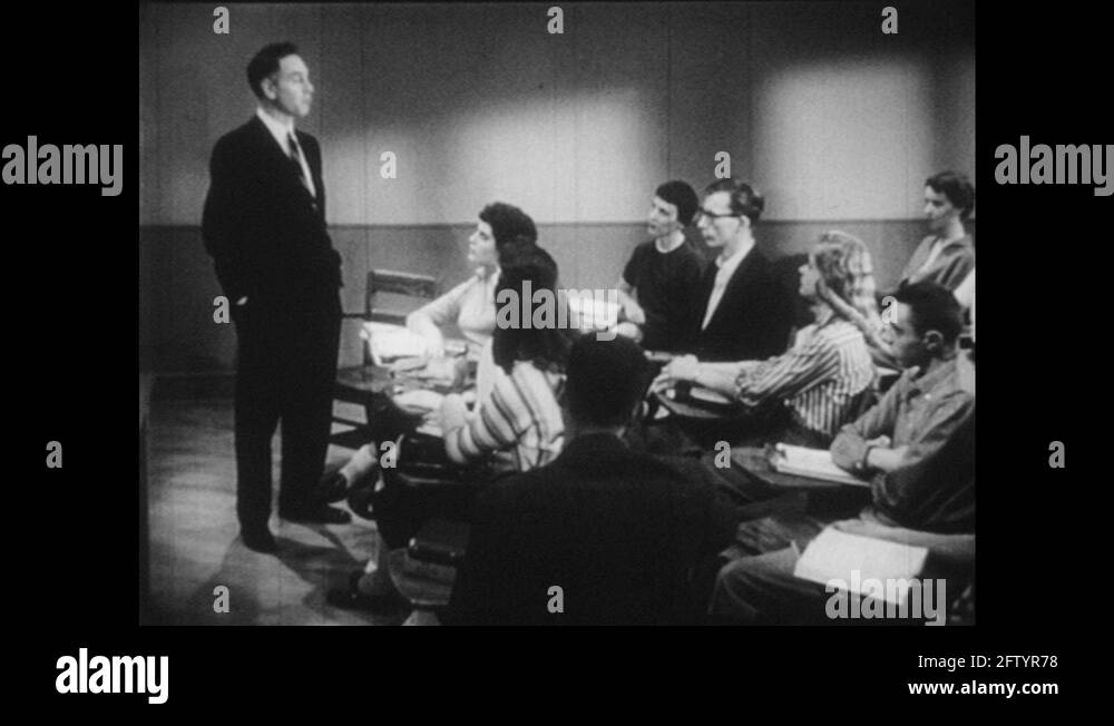 1950s: Male professor stands with hands in pockets in front of class ...