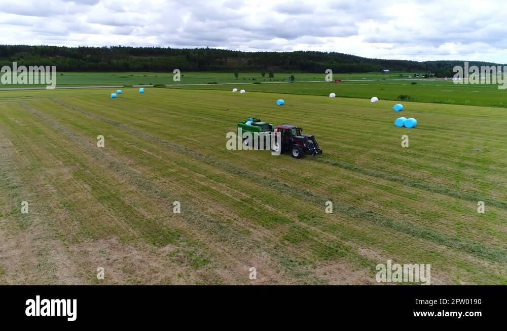 Baler machine, Cinema 4k aerial view around a baler leaving a hay ball ...