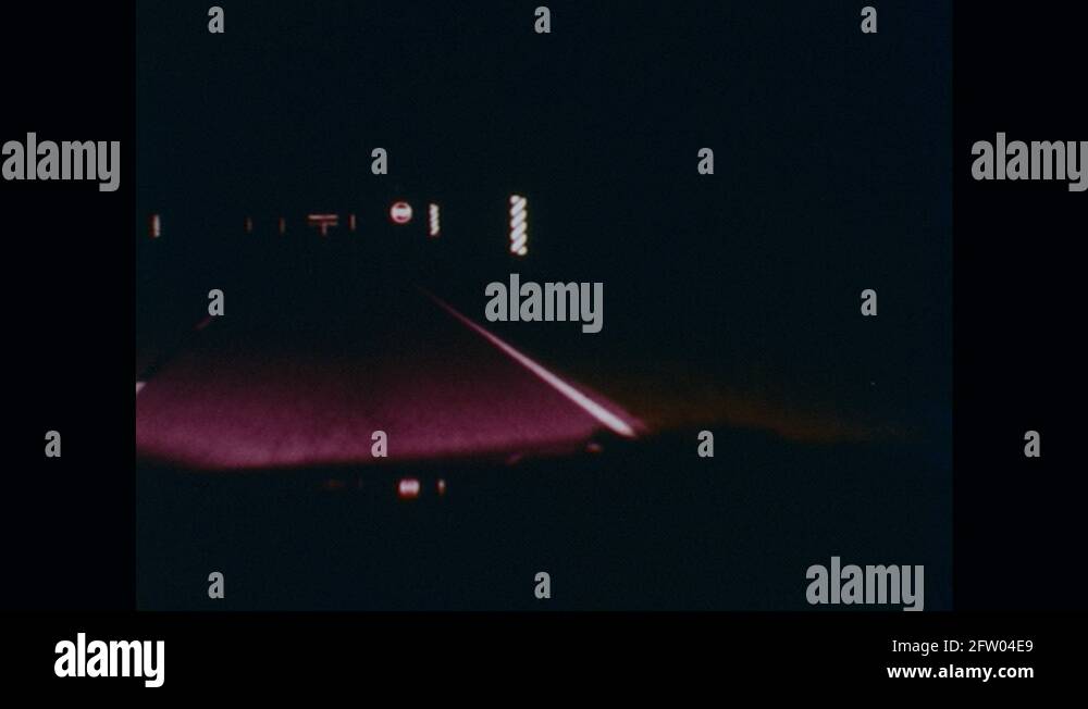 1960s: UNITED STATES: stop sign on side of road at night. Exit sign by ...