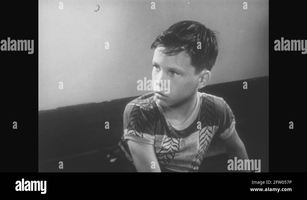 1950s: Boy sits on floor, nods, speaks. Man squatting in corner nods ...