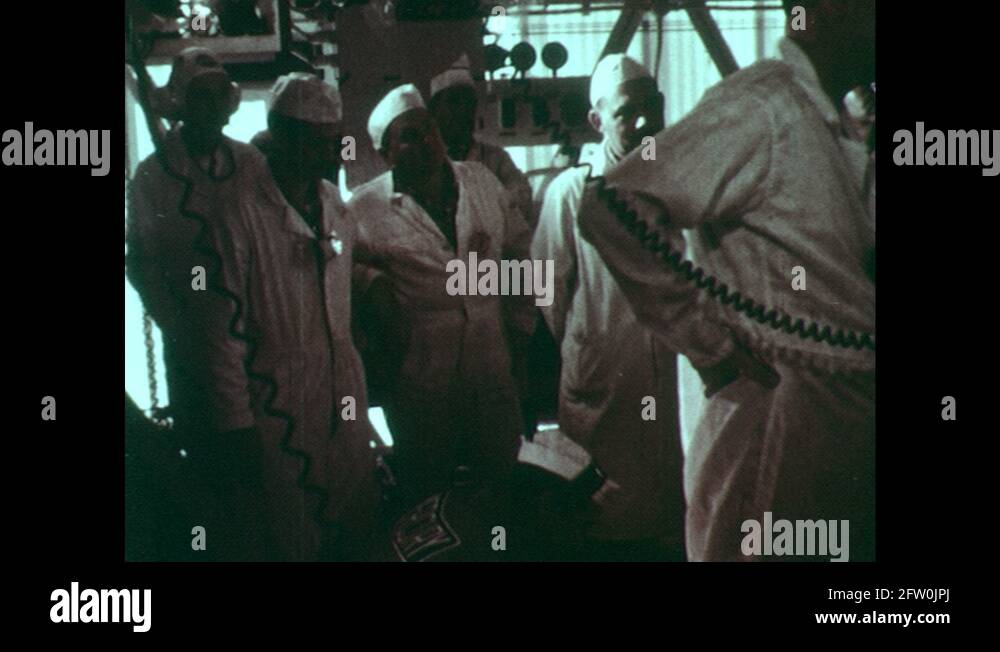 1960s: Group of men in white jumpsuits stand by space shuttle. Man ...