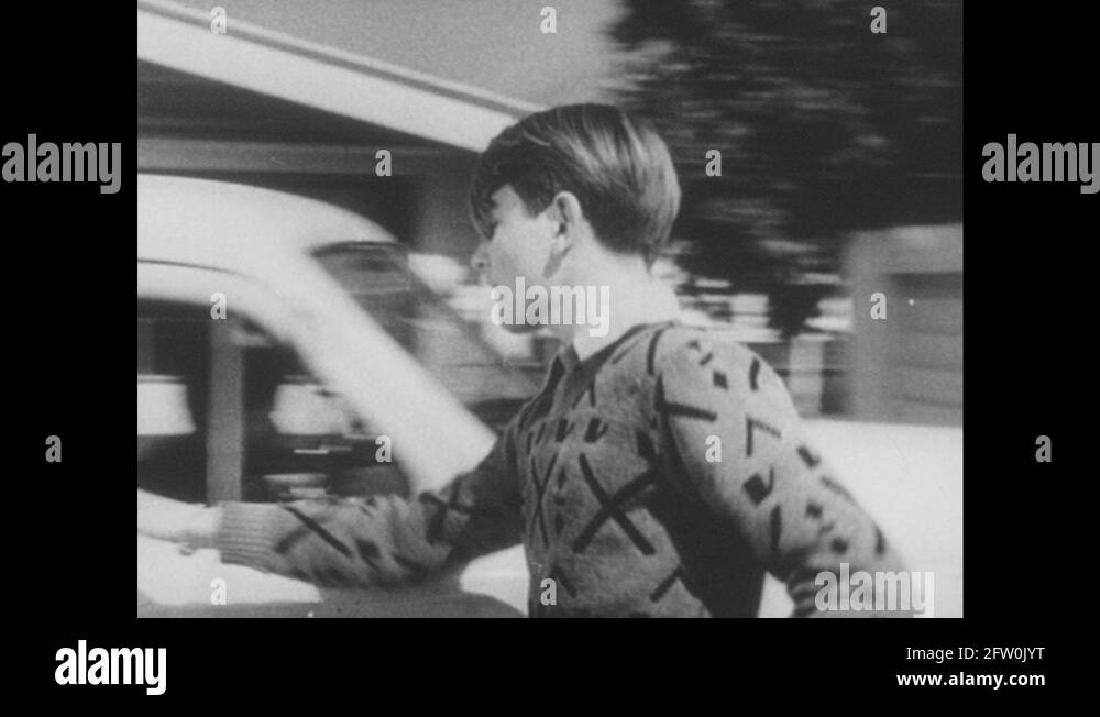 1950s: UNITED STATES: boy runs to car. Boy gets in car. Boys talk in ...