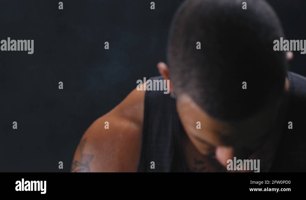 Sweating muscular black man staring at the camera on a foggy black ...