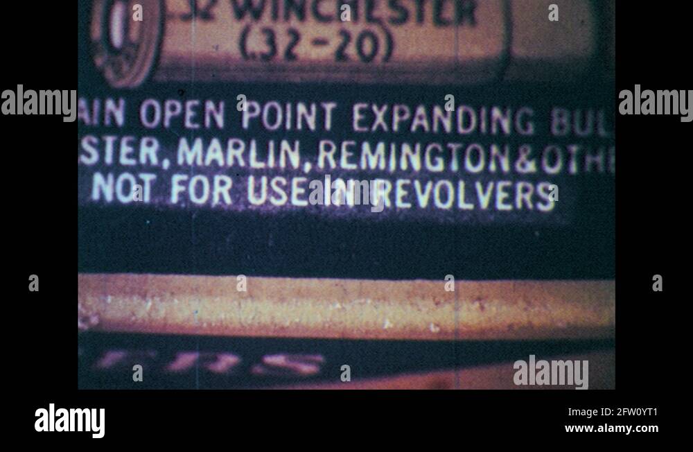 1950s: Close up of printed warning on box. Hands remove bullet from gun ...