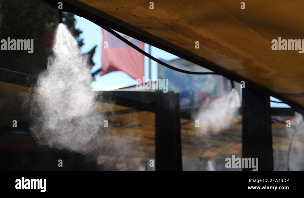 Cooling system on the street. Spraying a cold steam close up. Slow ...