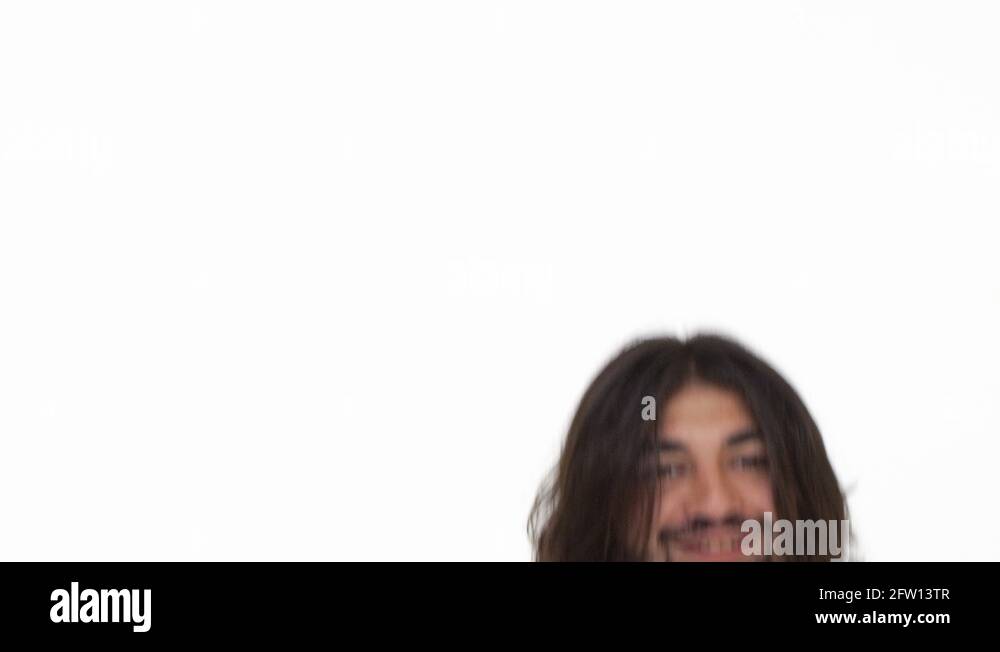 Merry guy with long hair jumping into frame isolated over white ...