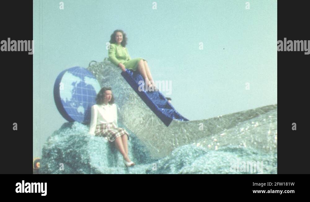 1940s: Women sit atop parade float shaped like airplane, wave. Float ...