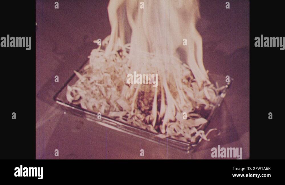 1950s: Tray of burning wood scraps is extinguished by a spray of water ...