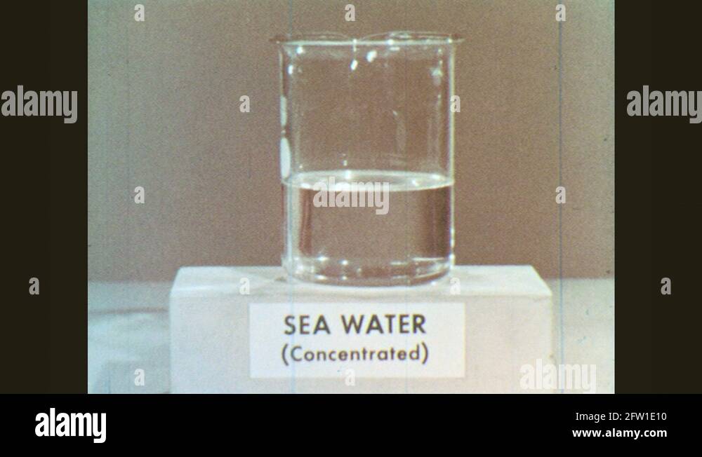 1960s: Beaker of sea water. Hand places litmus paper in sea water. Hand ...
