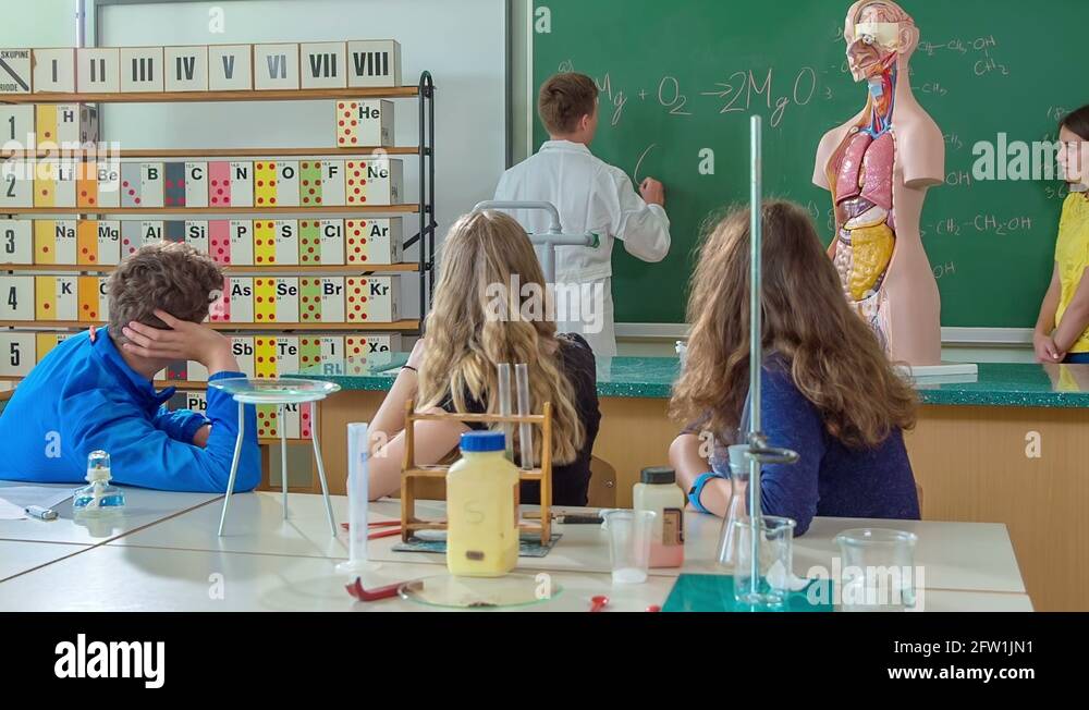 Boy is explaining something on the blackboard and other students are ...