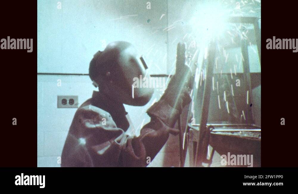 1950s: Boy welding. Sparks fly from welding torch. Boy takes off mask ...