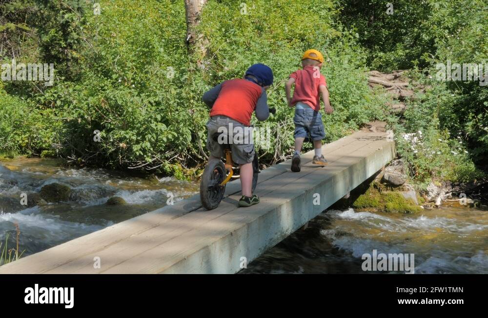 Two boys playing on and crossing a bridge over a river Stock Video ...