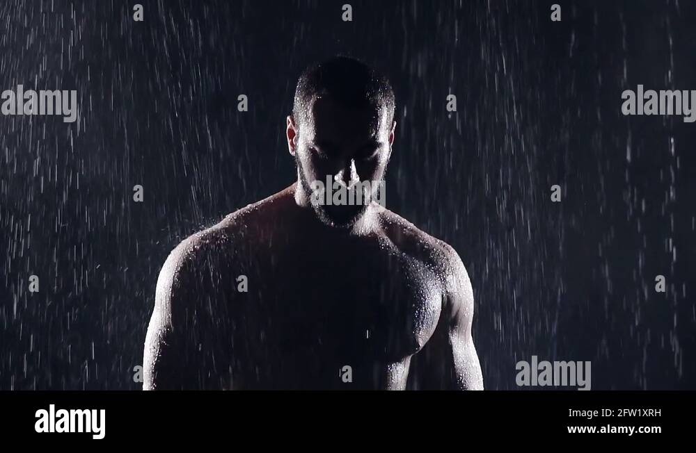 silhouette of a large muscular man bodybuilder in the rain it drains ...