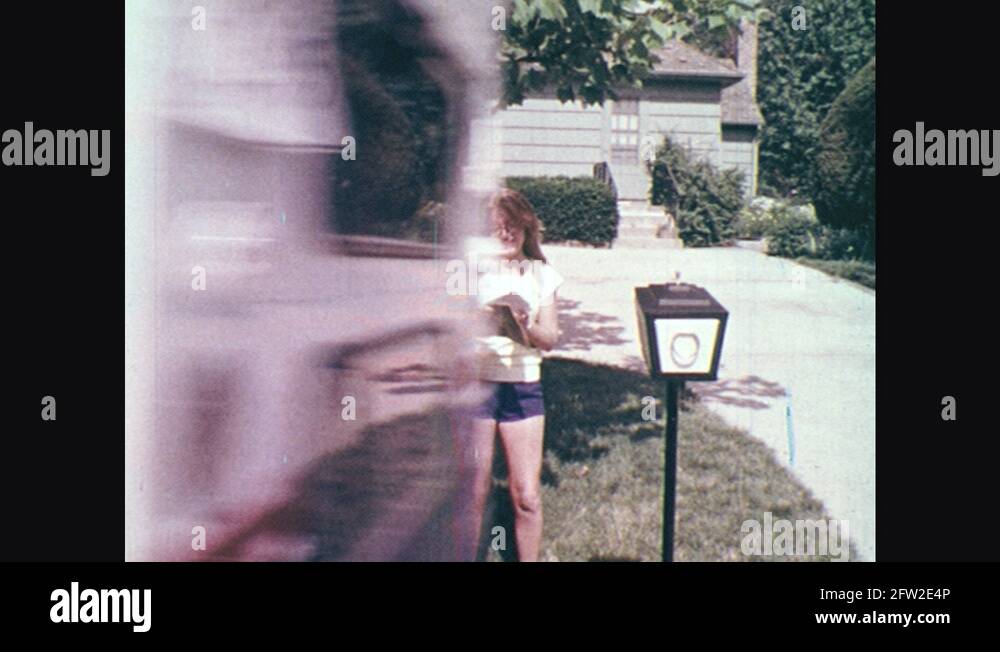 1970s: Mail truck. Girl stands in yard. Hands flip through mail. Girl ...