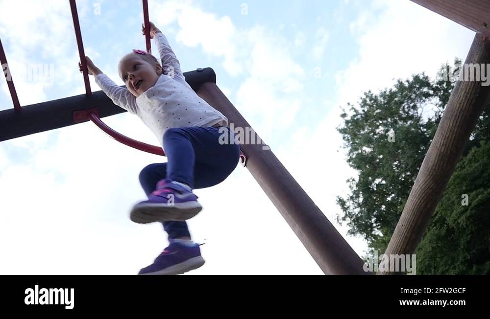 Little kid girl on park playground for children play hang sway on ...