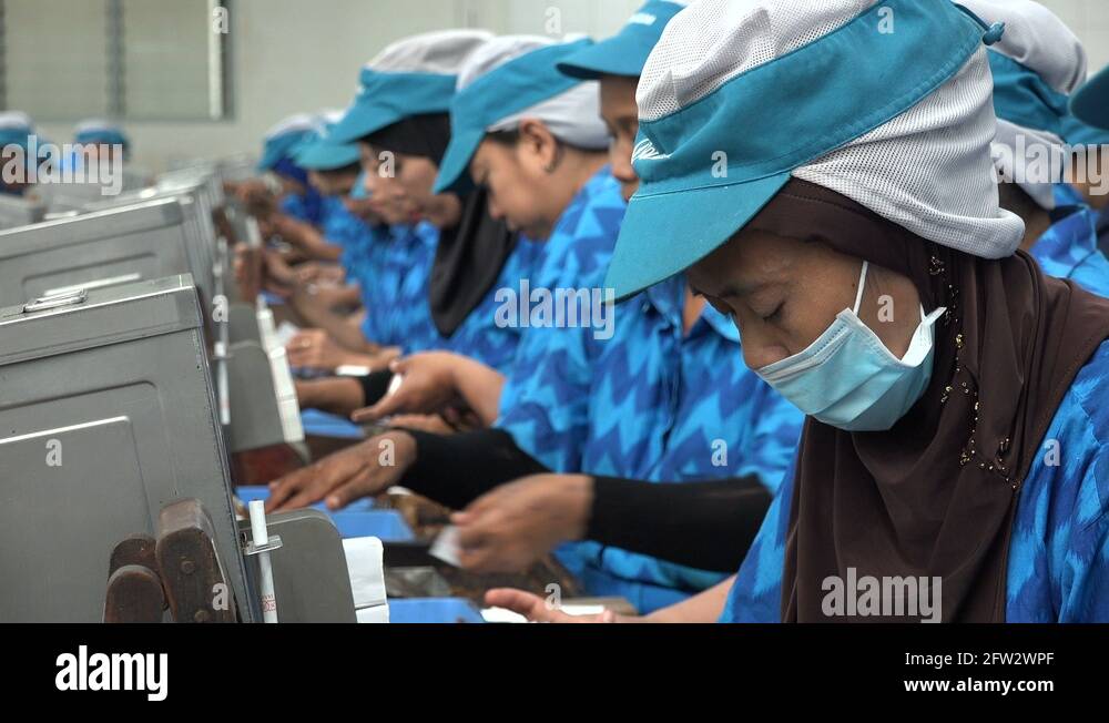 Female Muslim factory worker rolls cigarettes at production line ...