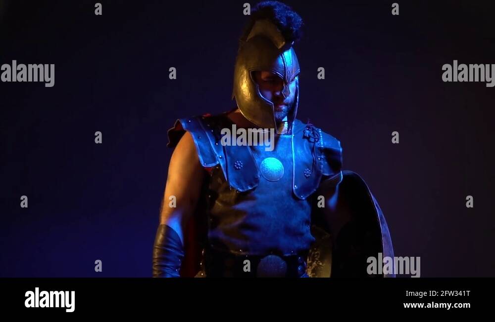 Unshaven Roman gladiator with a scar on his face in a helmet and armor ...