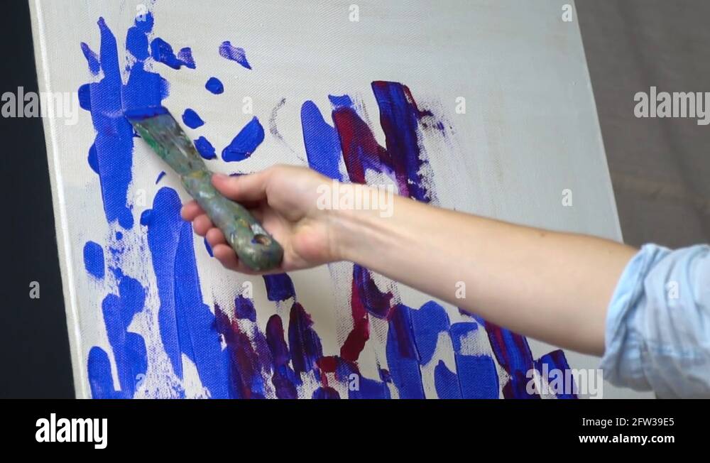 Female hands smeared in paint slowly smear with a spatula to drawing ...