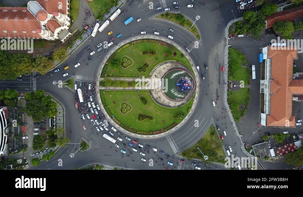 Motorbikes and cars use roundabout during rush hour Semarang, Indonesia ...