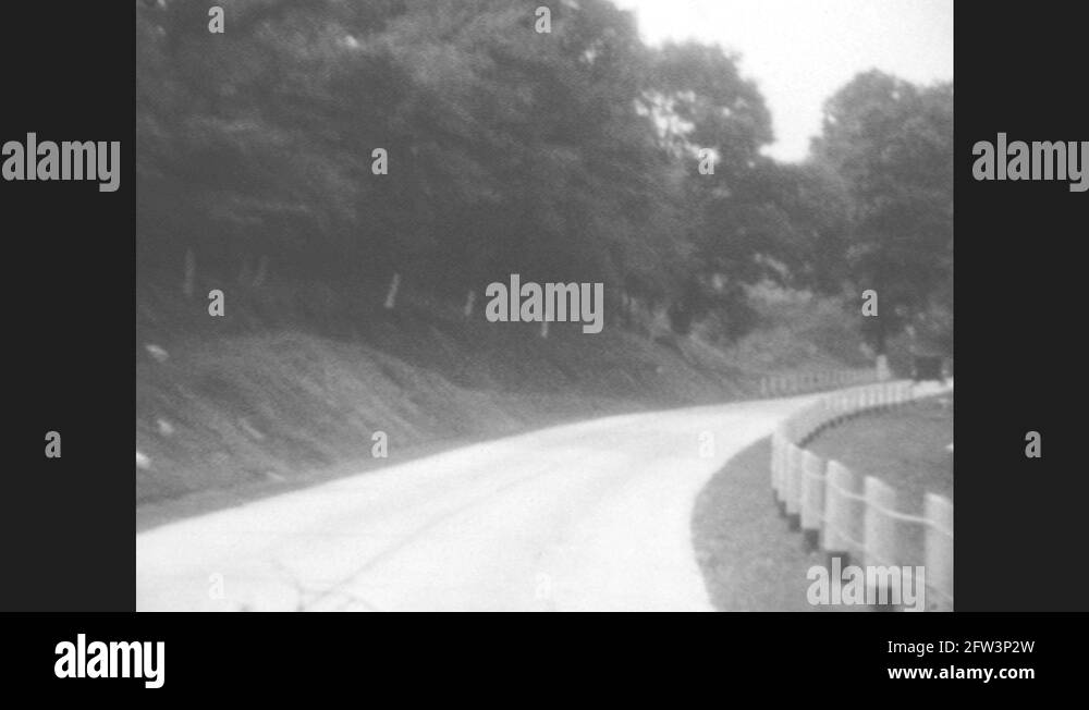 1920s: Vehicle driving along two-lane road in rural area with white ...