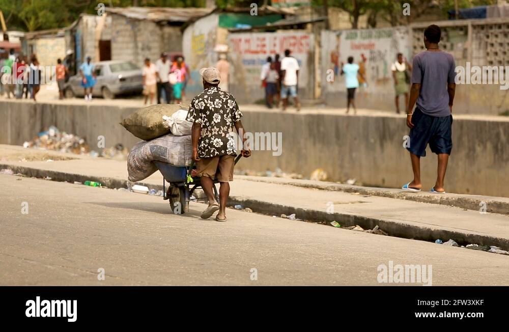 A man walks an overloaded wheelbarrow down a busy street in Port-au ...