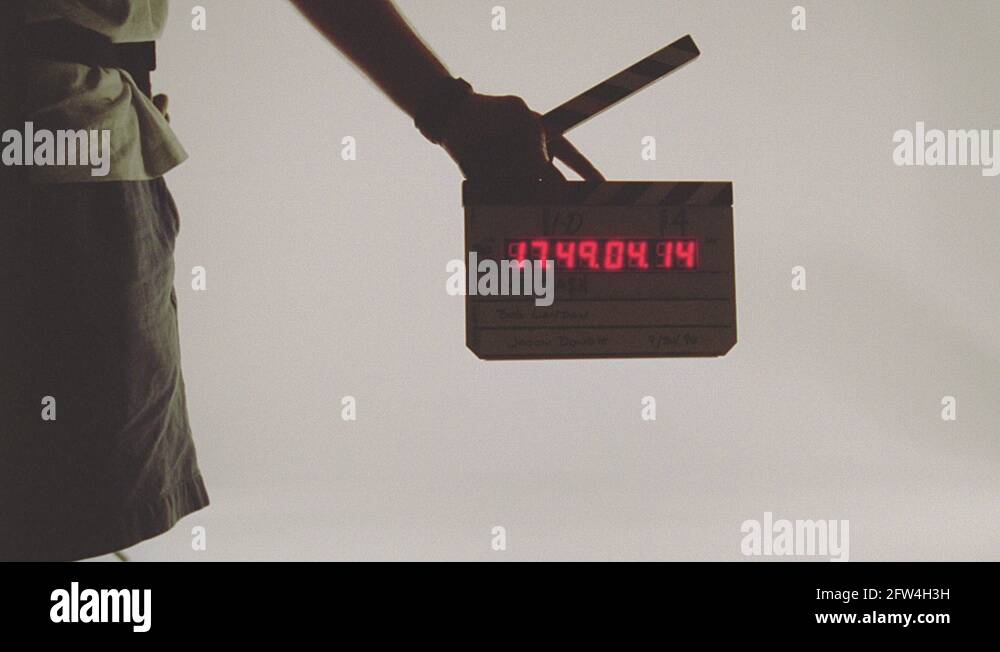 1990s: UNITED STATES: hand holds digital clapper board. Man walks in ...