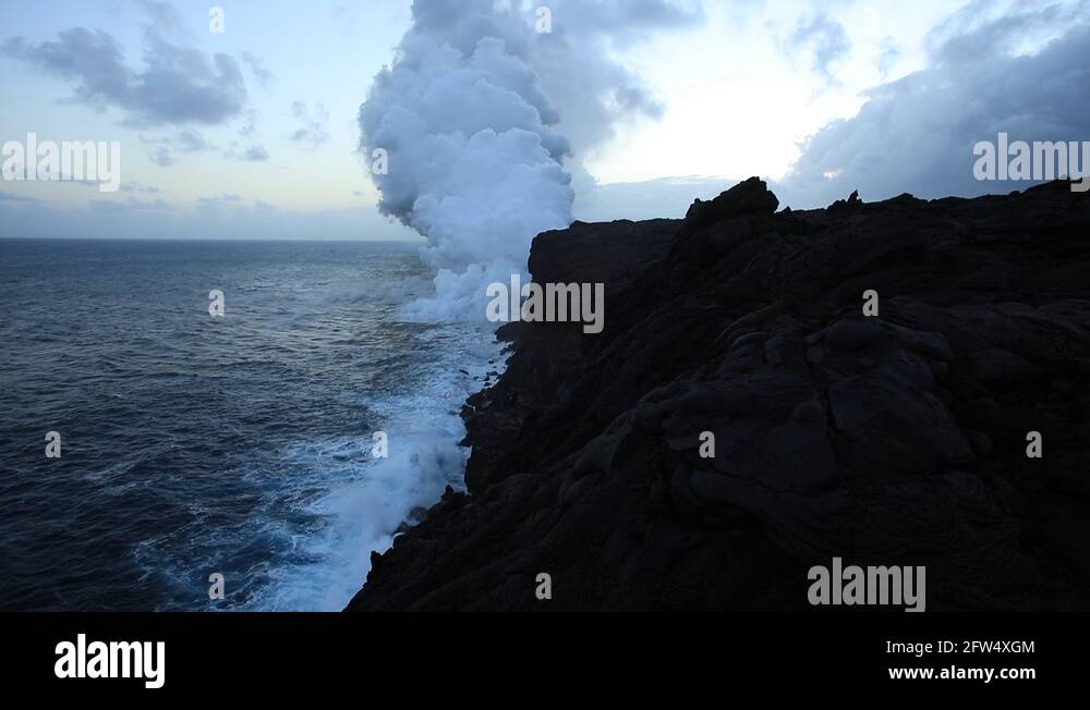 Lava flows after sunset into the ocean, steam cloud rising from water ...