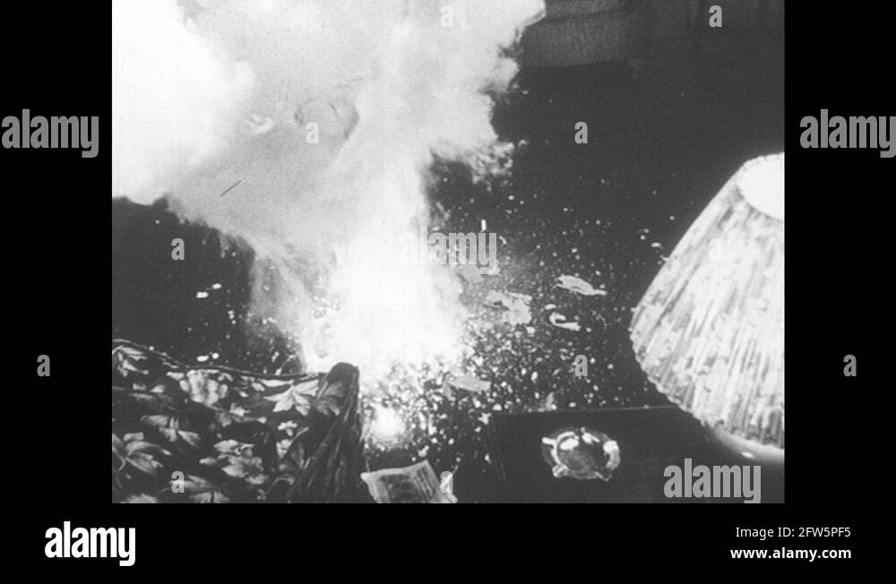 1940s: UNITED STATES: fire bomb explodes in house. Man hides behind ...